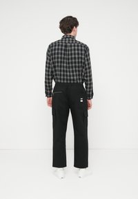 Former PRAYER - Pantalones cargo - black/negro - Zalando.es