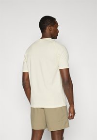 Puma OM PUMATECH POCKET TEE - Sports T-shirt - alpine snow/golden ...