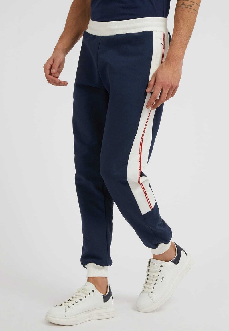 Guess MIT SEITENSTREIFEN - Tracksuit bottoms - blau/dark blue - Zalando.ie