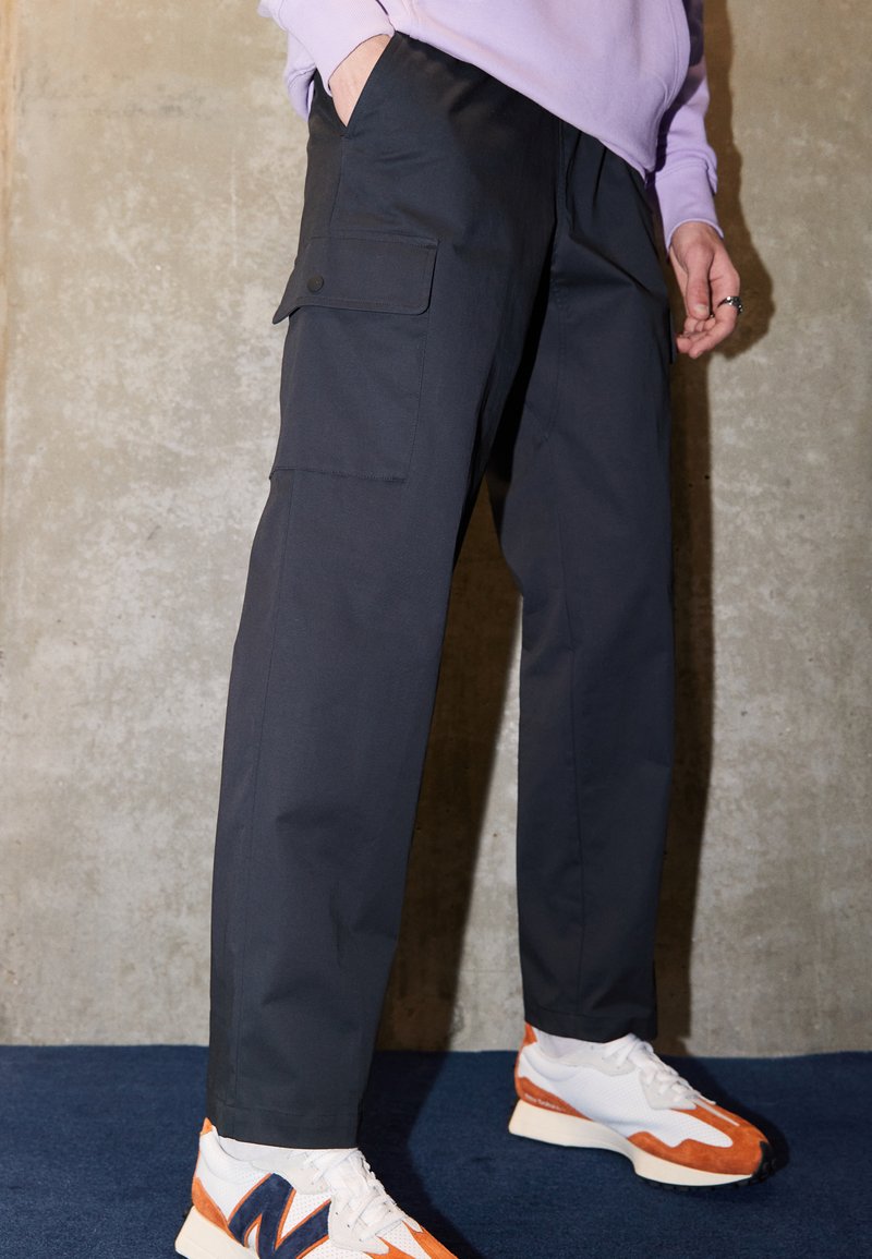 New Balance NB ATHLETICS - Cargo trousers - black - Zalando.ie