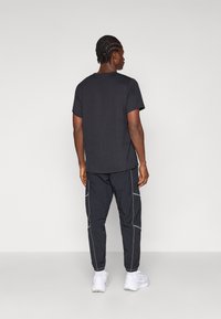 Nike Performance RETRO TRACK PANT - Verryttelyhousut - black/reflective ...