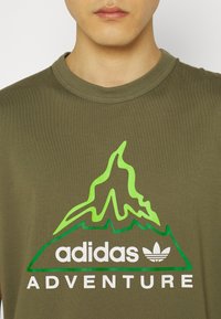 adidas Originals VOLCANO TEE - Camiseta estampada - olive strata/verde ...
