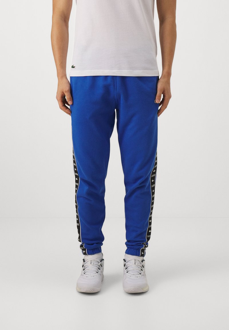 Lacoste Sport TROUSERS TAPE - Tracksuit bottoms - ladigue/blue ...